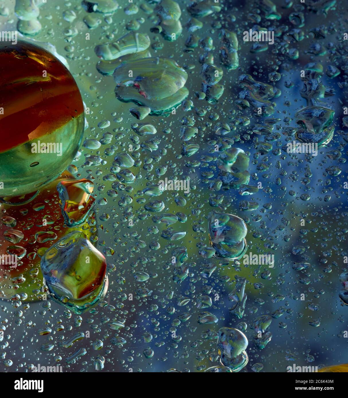 Coloured glass marbles with a background of colour infused water ...