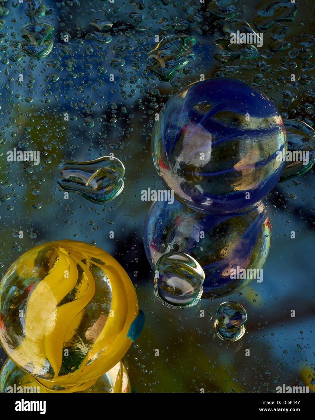 Coloured glass marbles with a background of colour infused water ...