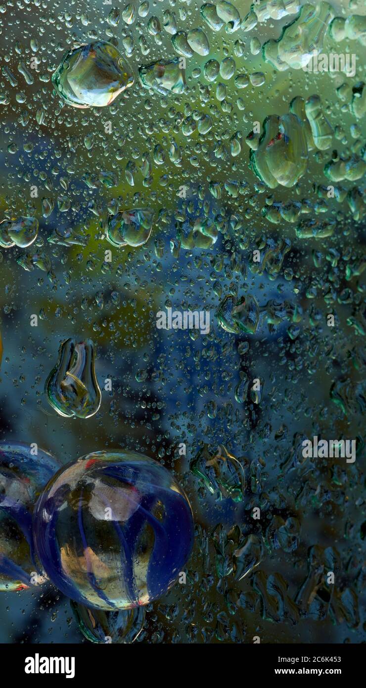 Coloured glass marbles with a background of colour infused water ...