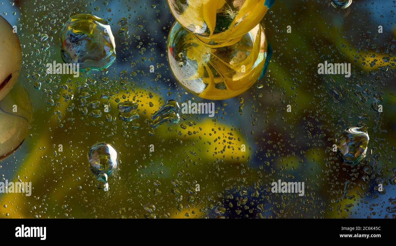 Coloured glass marbles with a background of colour infused water ...