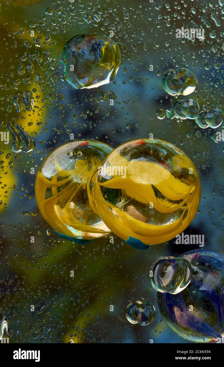 Coloured glass marbles with a background of colour infused water ...