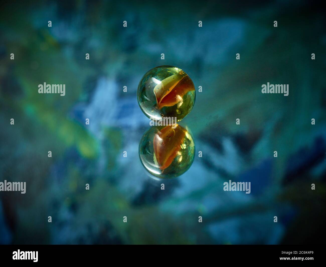 Single glass marble and reflection with a colour infused background and ...