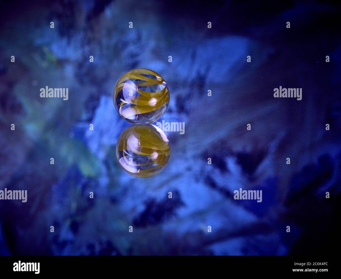 Single glass marble and reflection with a colour infused background and ...