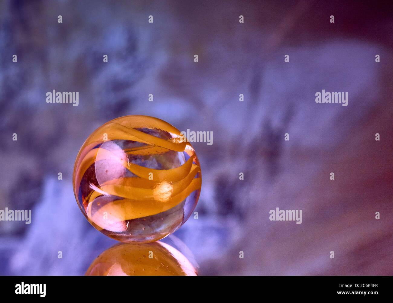 Single glass marble and reflection with a colour infused background and ...