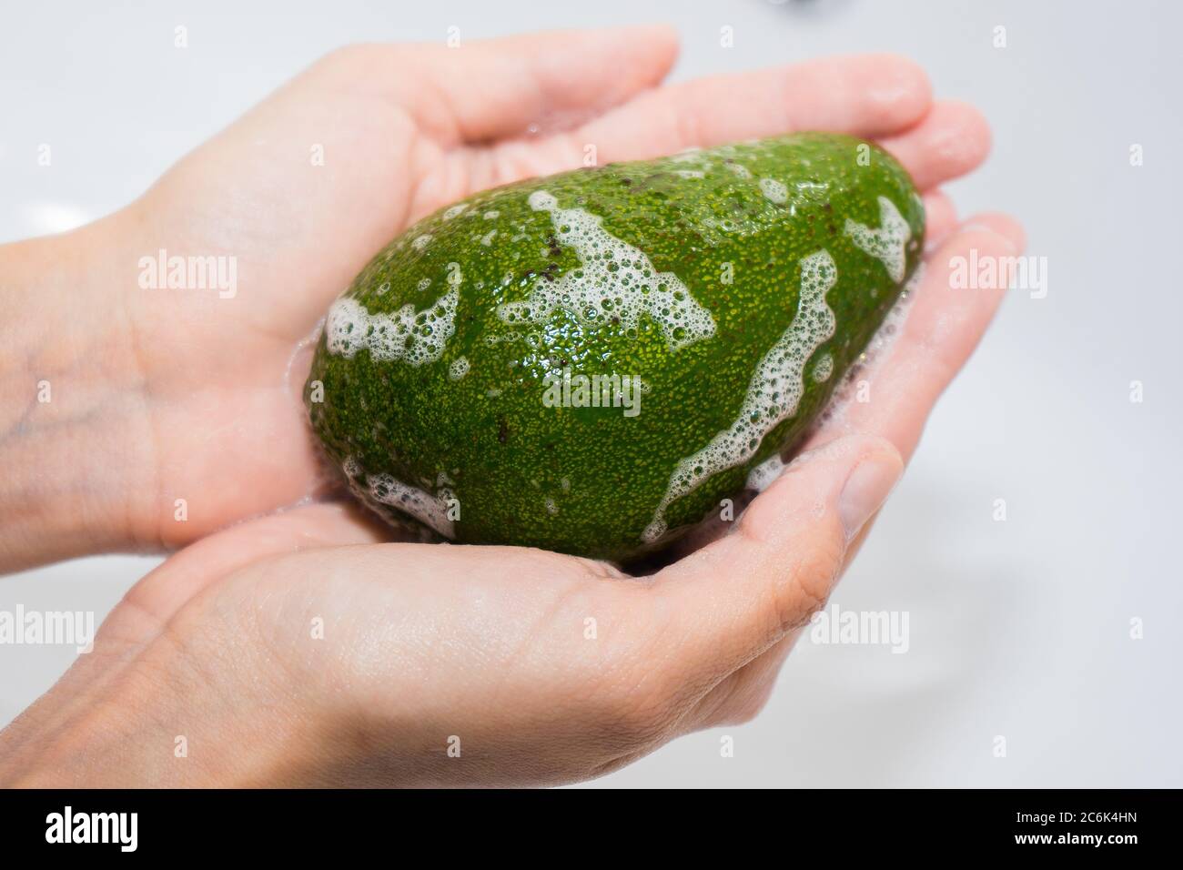 washing fruit with soap and foam. Wash avocados. Hands and soapy green ...