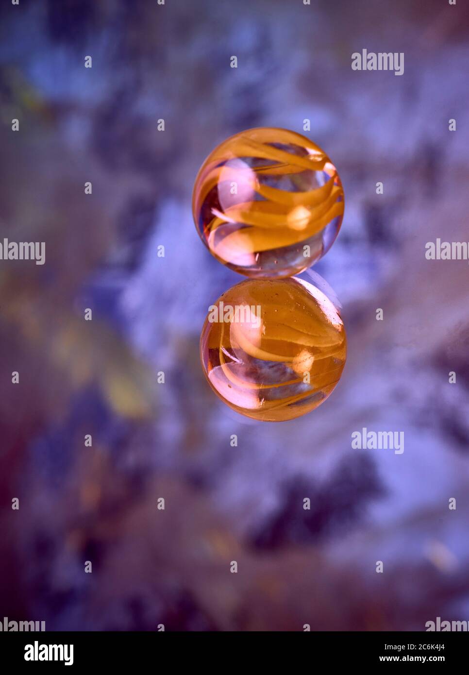 Single glass marble and reflection with a colour infused background and ...