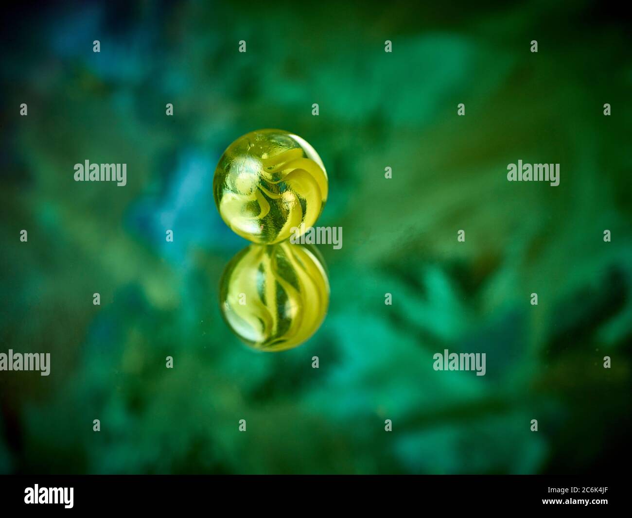 Single glass marble and reflection with a colour infused background and ...