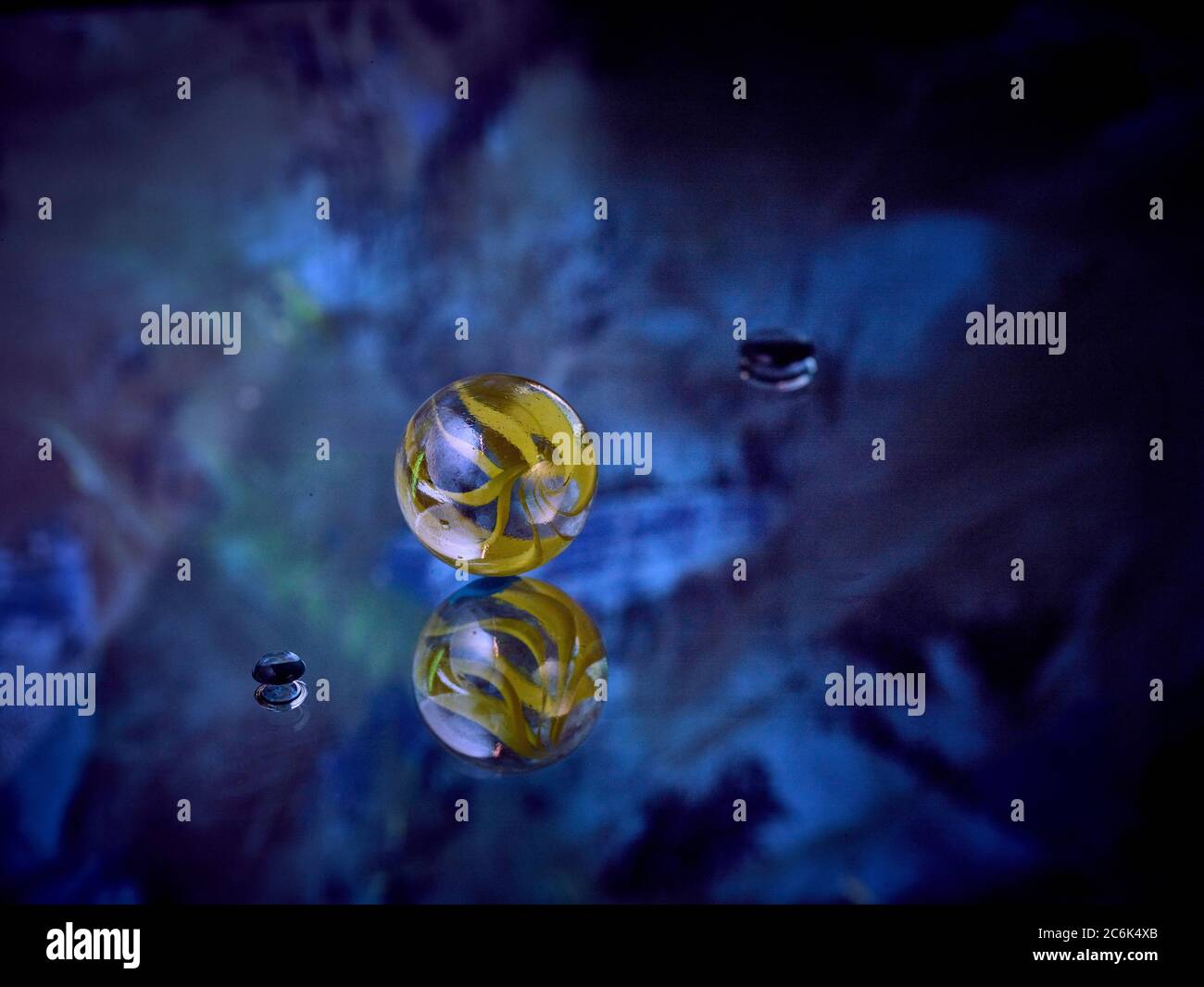 Coloured glass marbles with a background of colour infused water ...