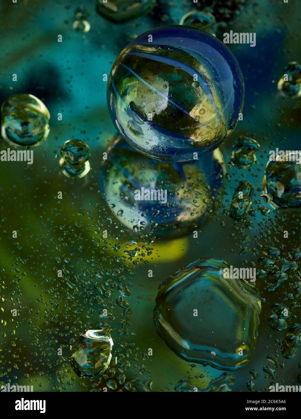 Coloured glass marbles with a background of colour infused water ...