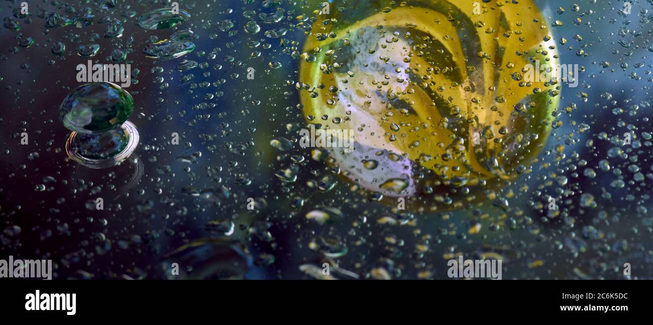 Coloured glass marbles with a background of colour infused water ...