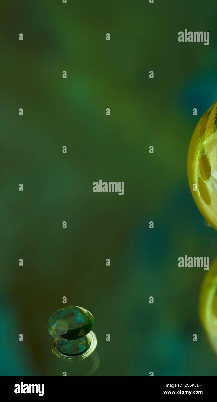 Coloured glass marbles with a background of colour infused water ...