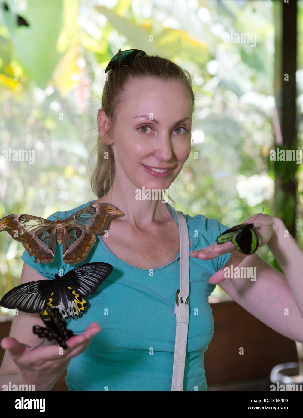 beautiful young woman in a butterfly park with large tropical ...