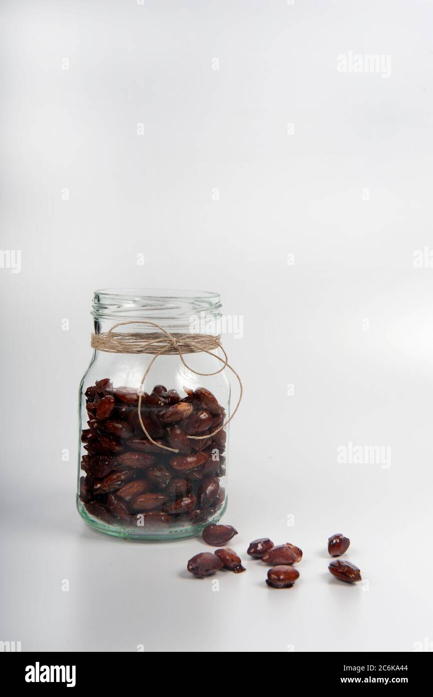 Open jar with burnt almonds. White background with copy space in the ...