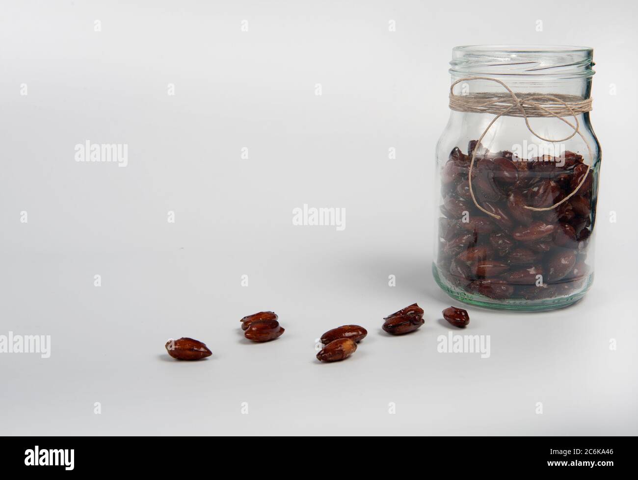 Open jar with burnt almonds. White background with copy space in the ...