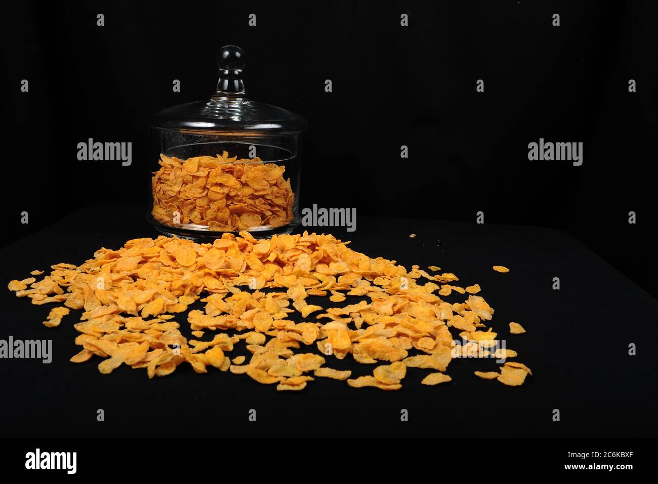 Big glass jar with lid containing corn flakes. Corn flakes spread out ...