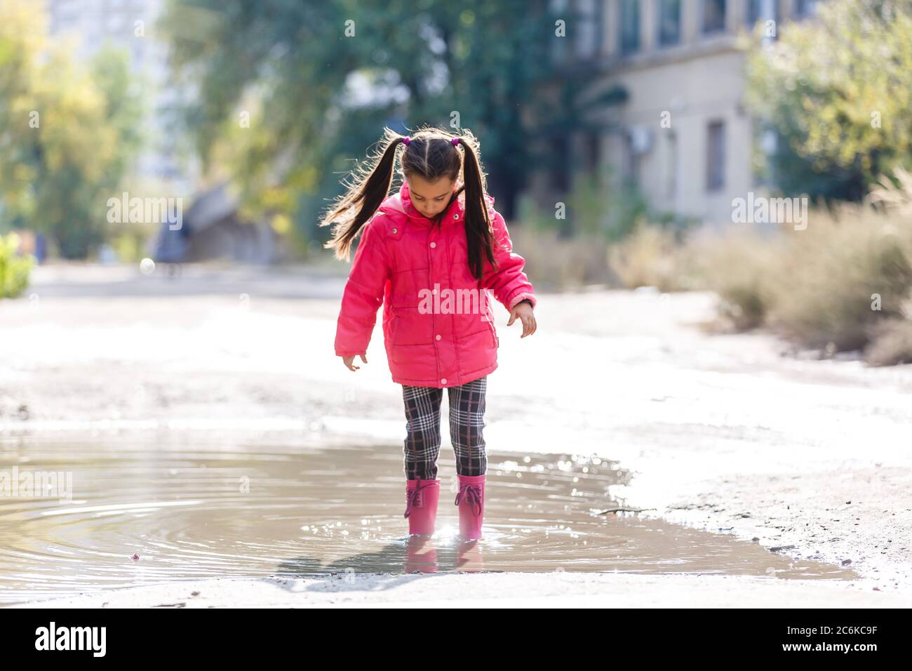 Adorable little girl standing in a puddle on warm autumn day Stock ...