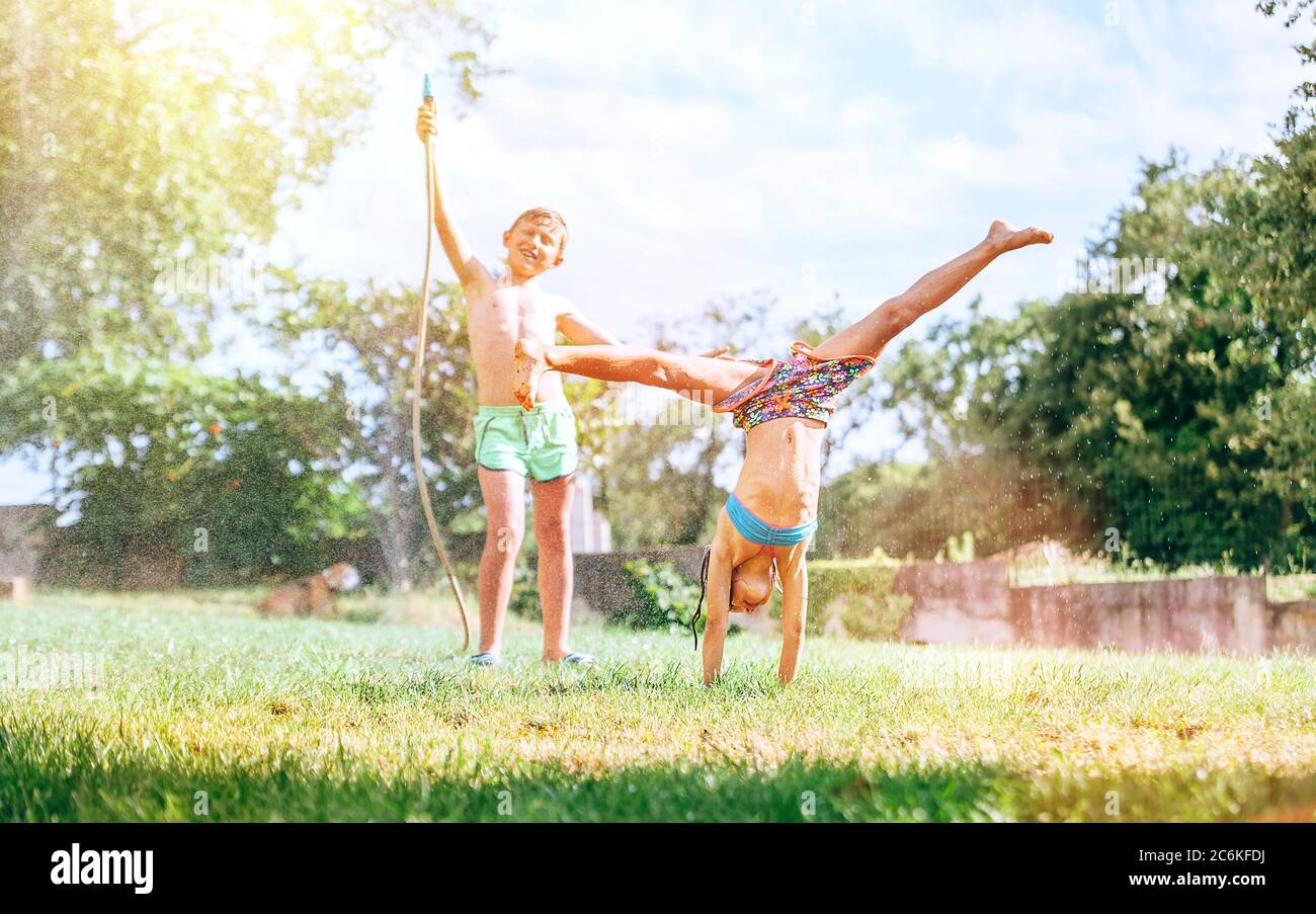 Happy children fool around in the summer garden, splashing water and ...
