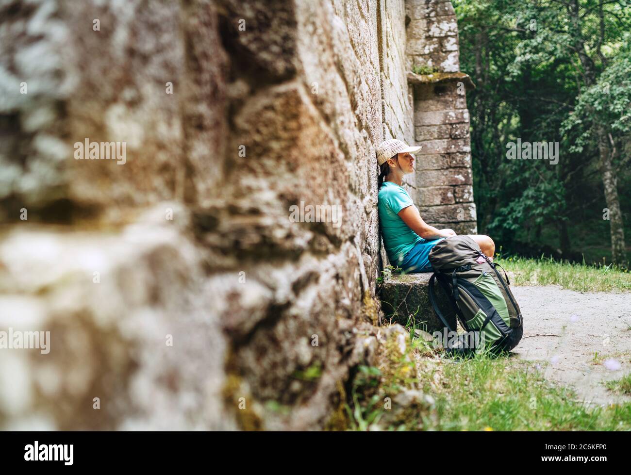 Tired female backpacker resting on the bench near the old antique brick ...