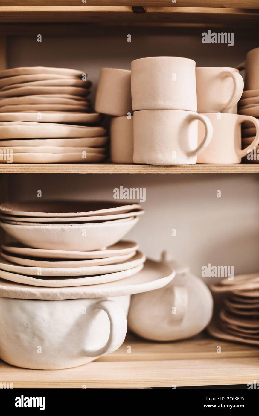 Close up handmade classic clay dishes on wooden shelves at pottery ...