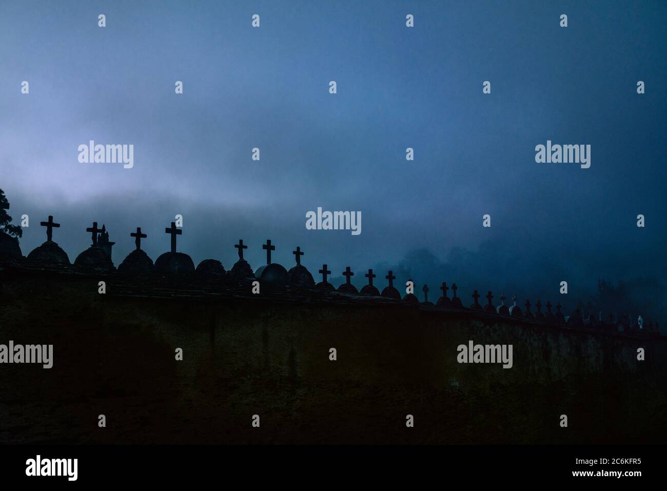 Creepy spooky graveyard atmosphere in the cemetery with tombstone and crosses in the foggy night ...