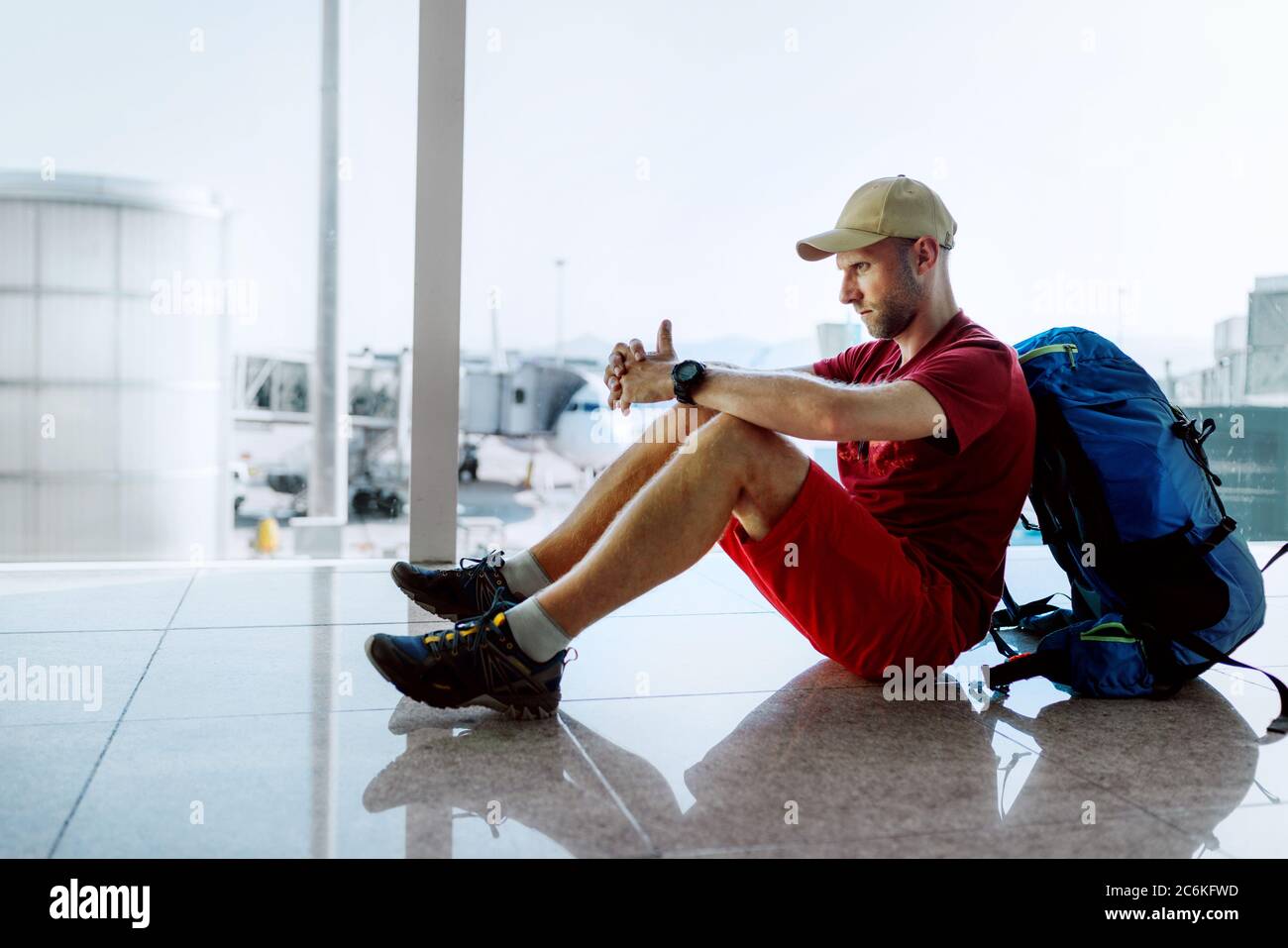 Alone backpacker traveller sitting on the airport terminal floor and ...