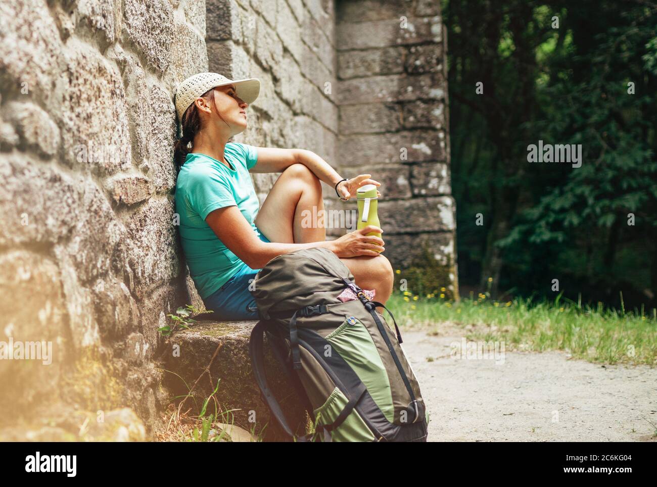 Very tired female backpacker resting on the bench near the old antique ...
