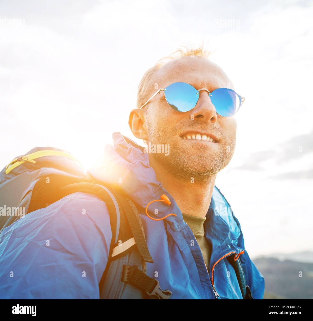 Backpacker man lifestyle portrait enjoying mountain landscape. He wears ...