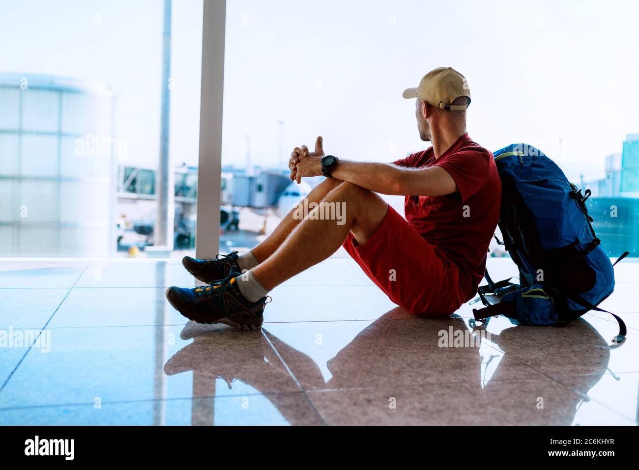 Alone backpacker traveler sitting on the airport terminal floor ...