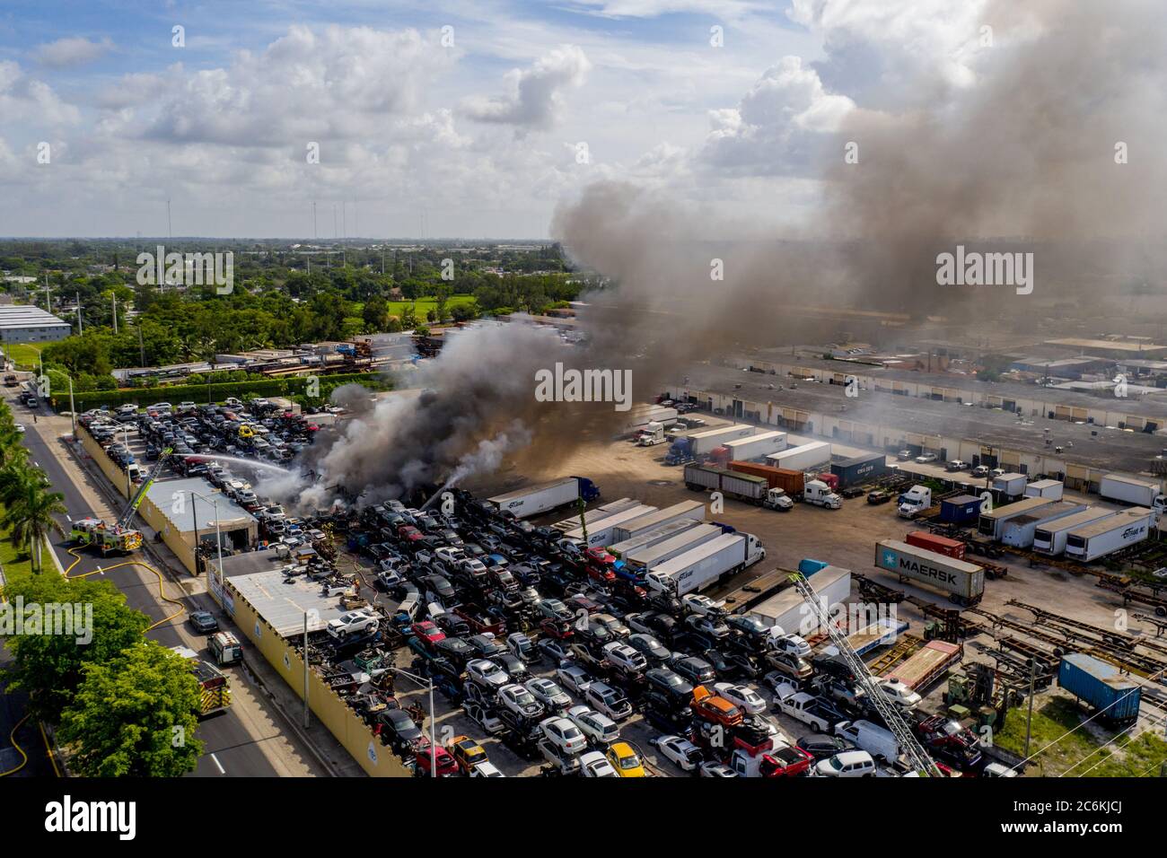 Aerial photo of a fire at a car junk yard firefighters water hosing ...