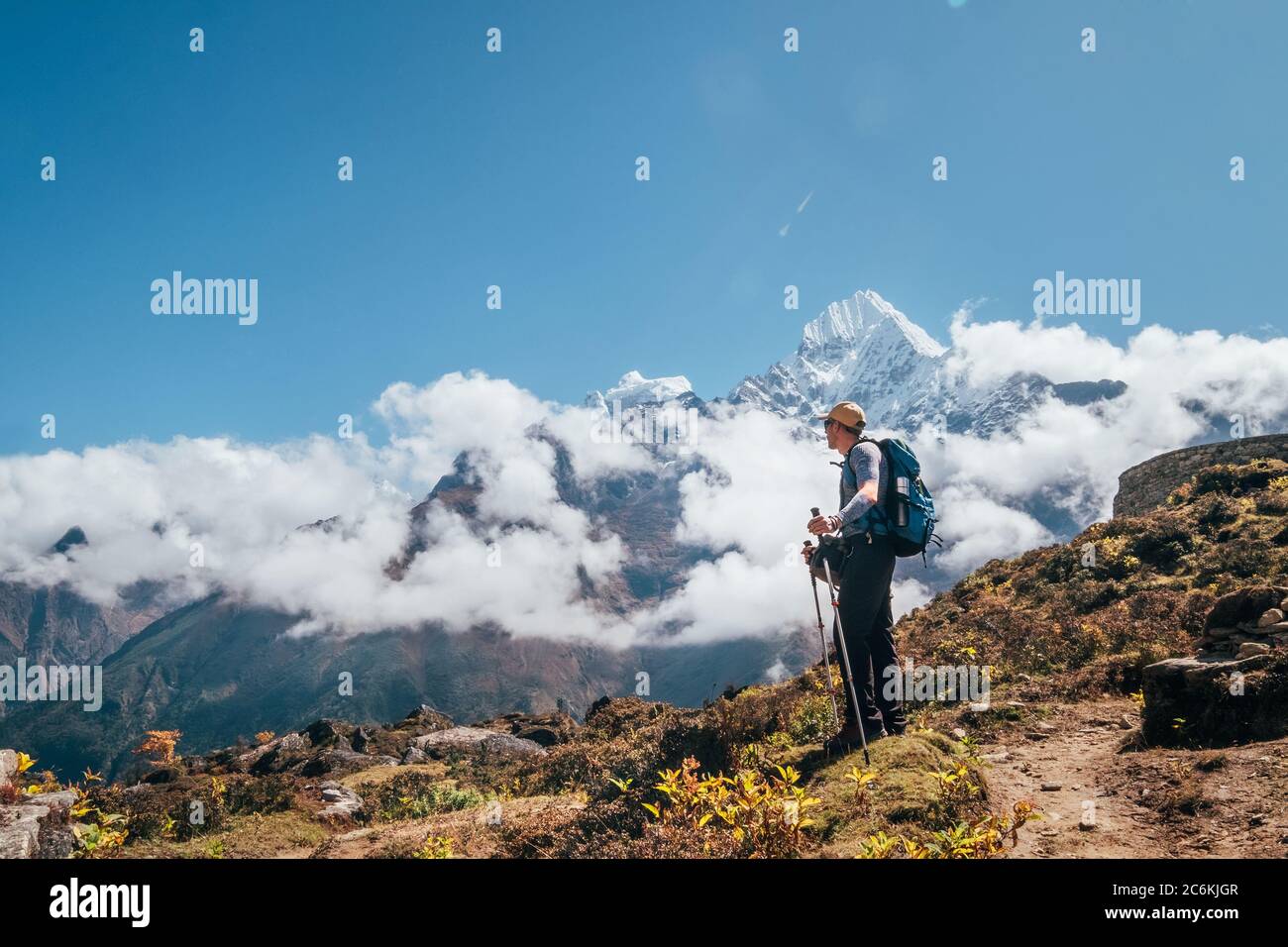 Young hiker backpacker man using trekking poles enjoying the Thamserku ...