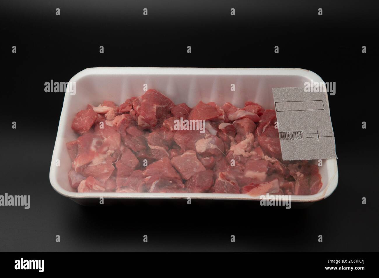 Raw diced meat (chopped in cubes) in a white styrofoam container with ...
