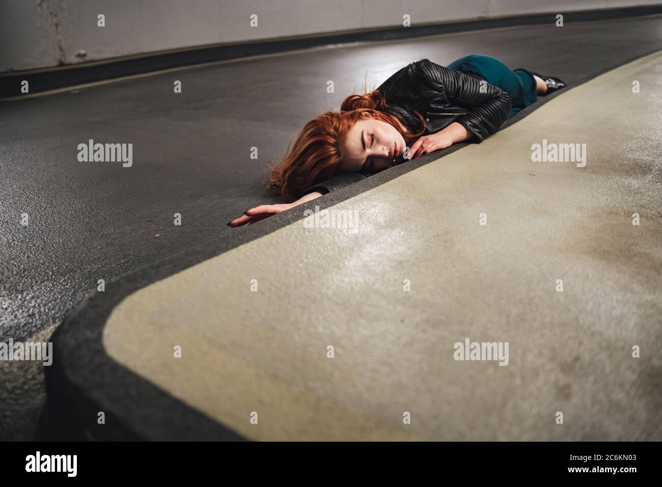 Red haired millennial female model laying on floor inside parking house ...