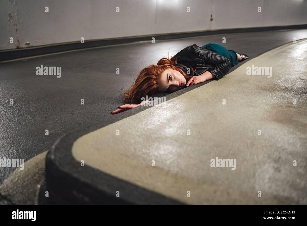 Red haired female model laying on floor inside parking house along curb ...