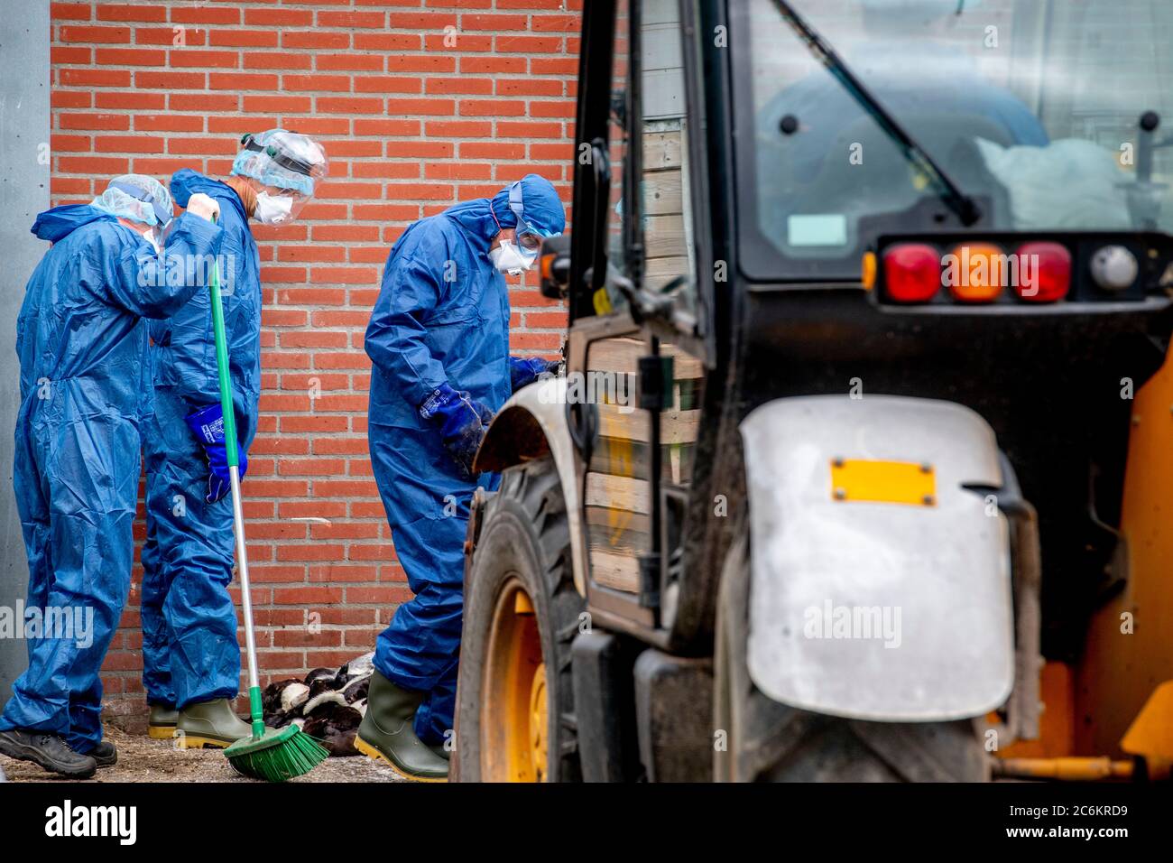 Workers wearing personal protective equipment (PPE) prepare to clean ...