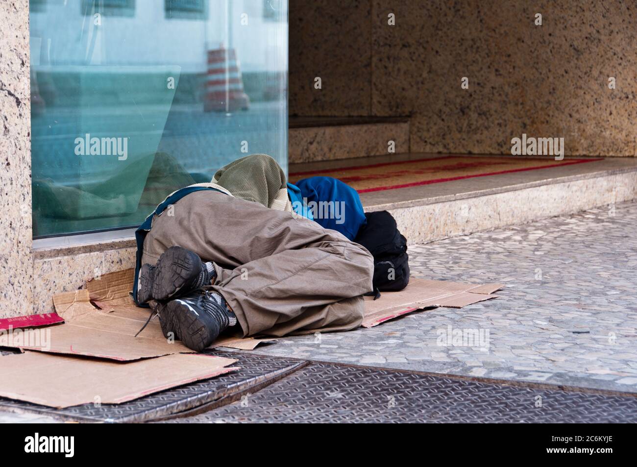 Homeless man sleeping on the paper in front of the commercial building ...