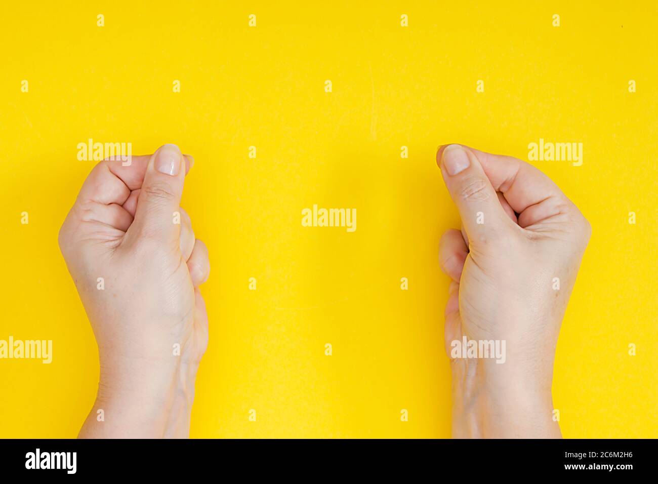 Hands with clenched fingers in a pinch on a yellow background Stock ...