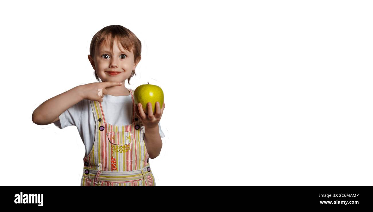 Portrait of a little girl pointing to a green apple on white background ...