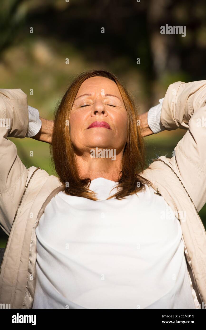 Portrait attractive mature woman sitting relaxed and happy outdoor ...