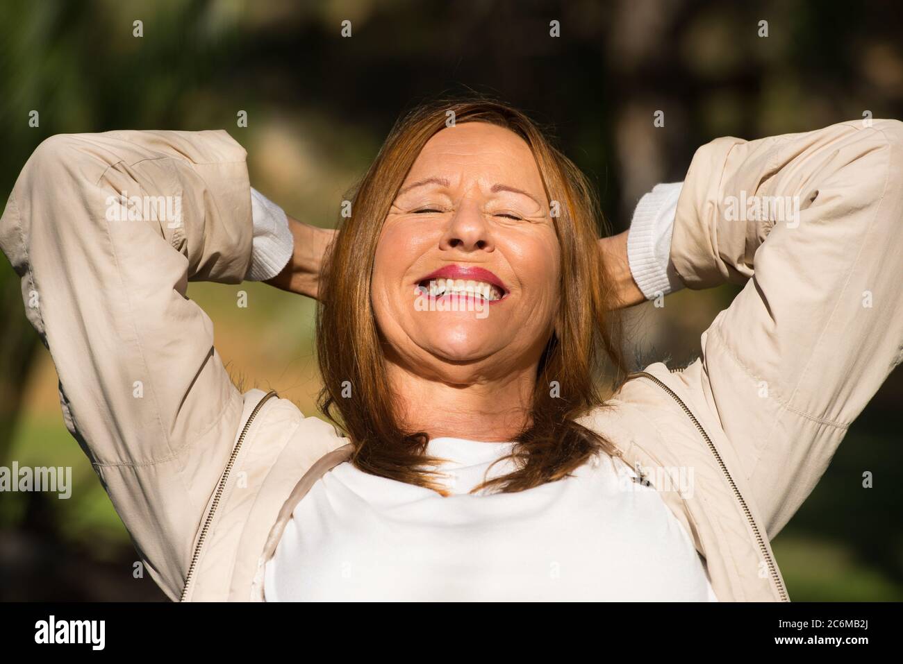 Portrait attractive mature woman sitting relaxed and happy outdoor ...