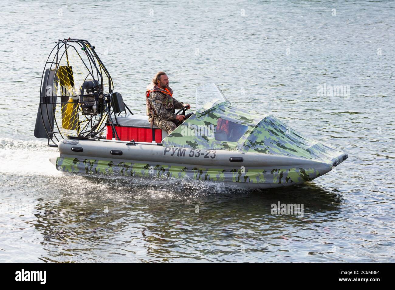 Man in camouflage uniforms and life jacket riding airboat along water ...