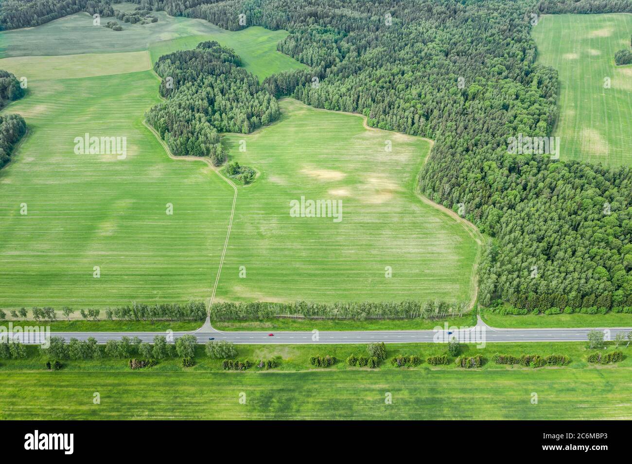 aerial view of a country road with cars between agricultural fields in ...