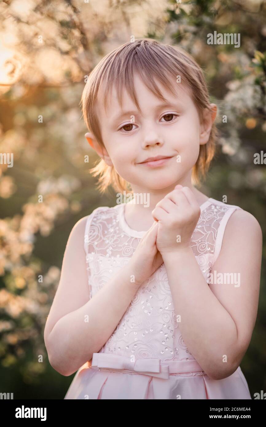 Cute little Girl r next to a blossoming apple tree at sunset Stock ...