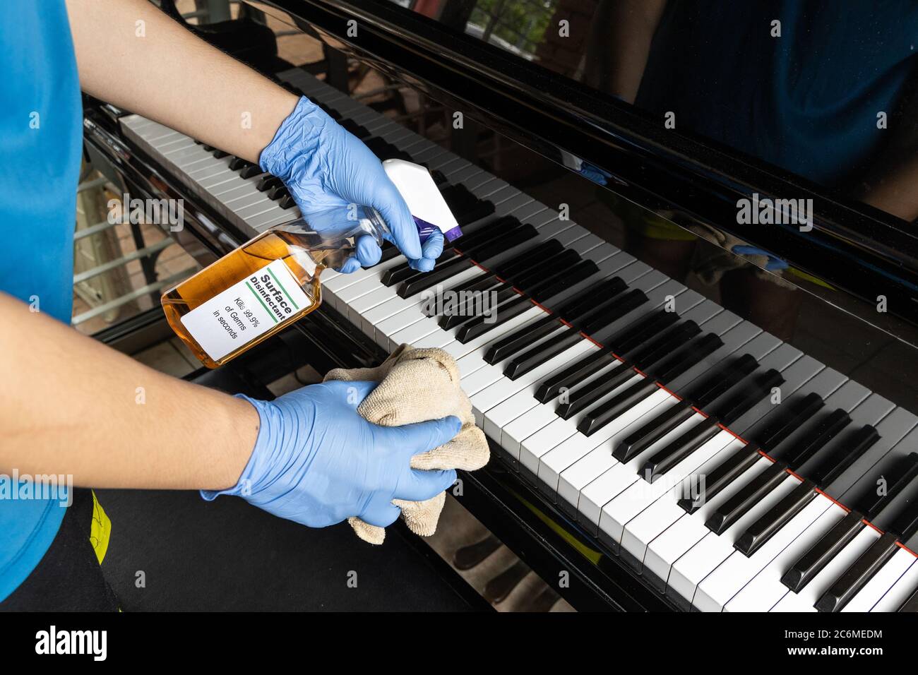Person in gloves disinfecting piano keyboard surface with disinfectant ...