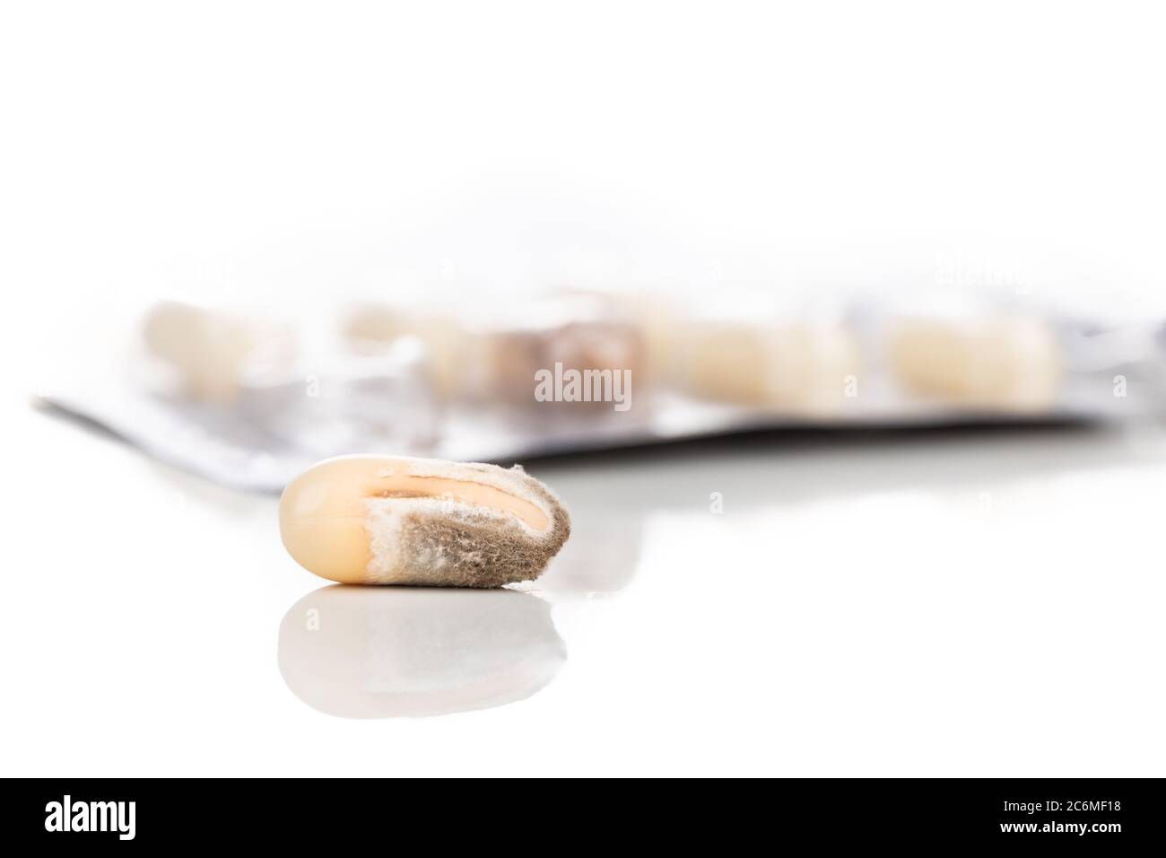 Strip of expired soft gel caplet medicine with mold on white background ...