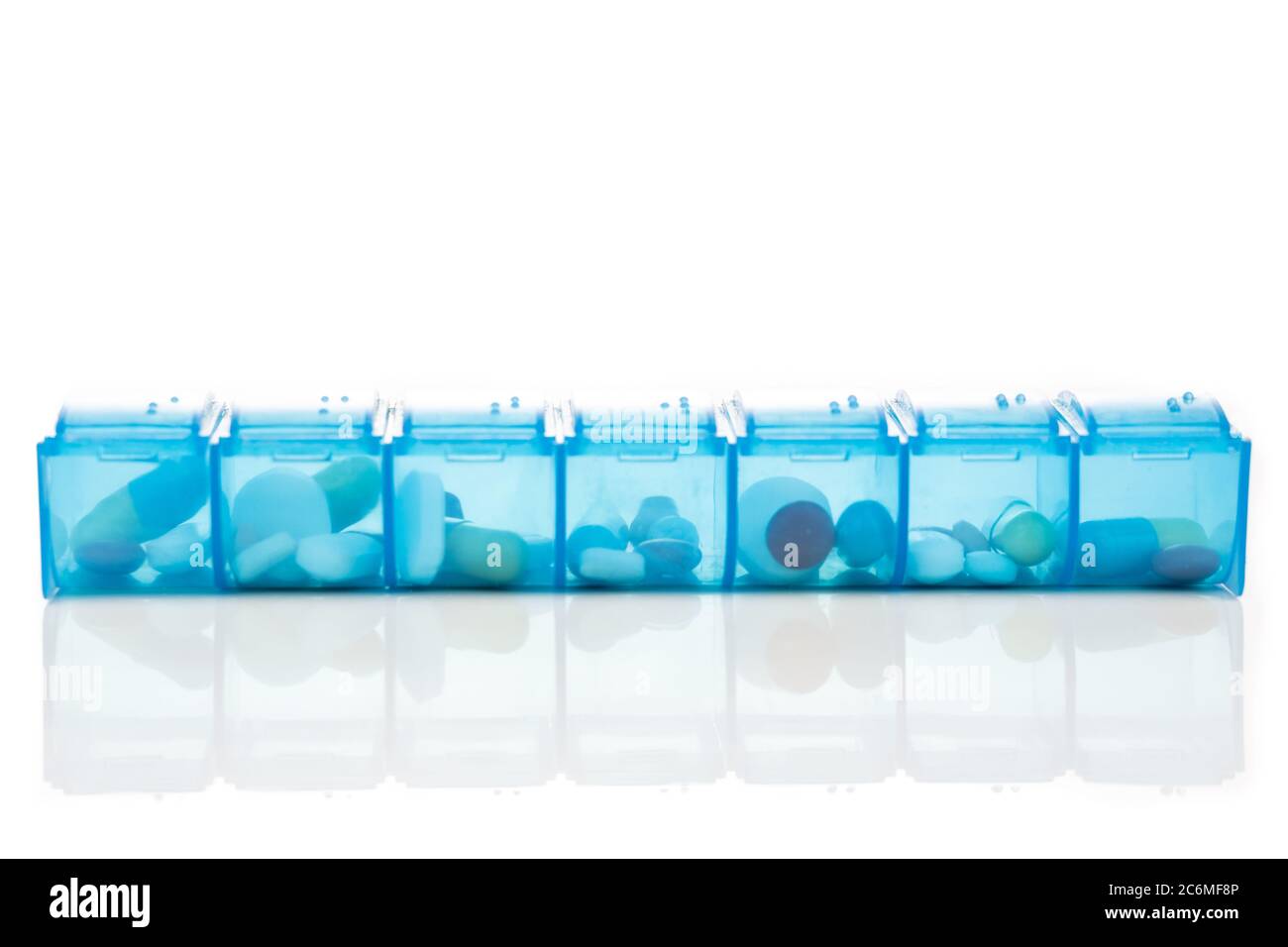 Pill organizer box storing doses of daily medicine on white background ...