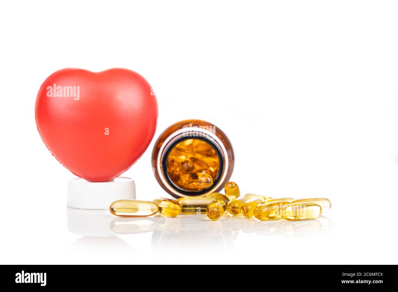 Fish oil gel capsule with bottle and heart shaped prop against white ...