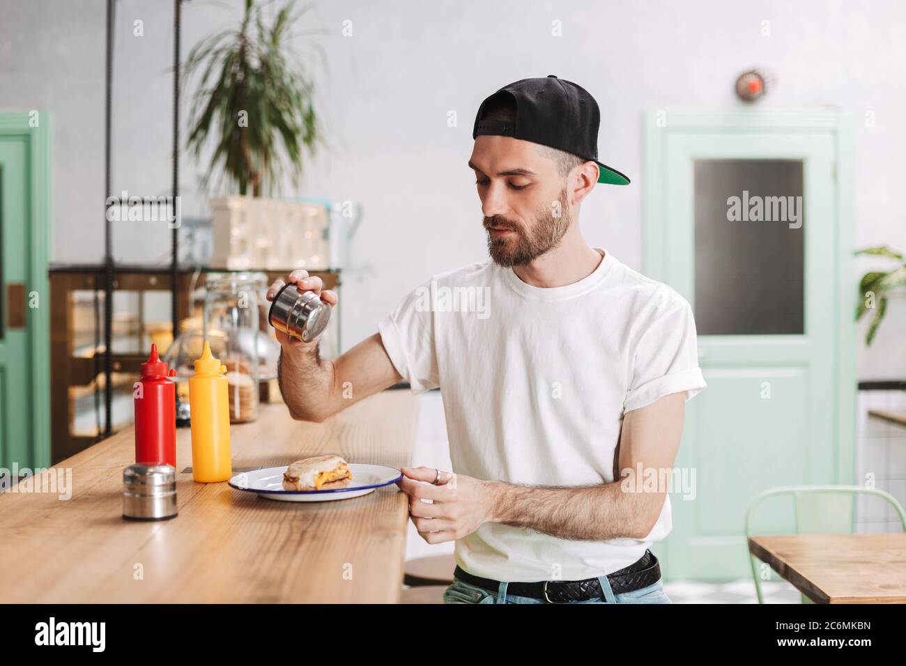 Young thoughtful man in black cap sitting at the bar counter and ...