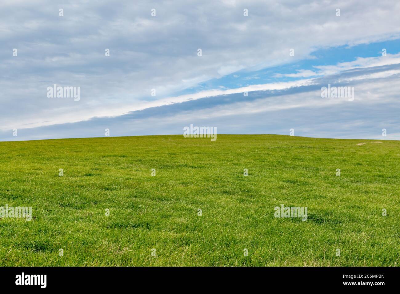 A grassy hillside with a blue sky overhead Stock Photo - Alamy