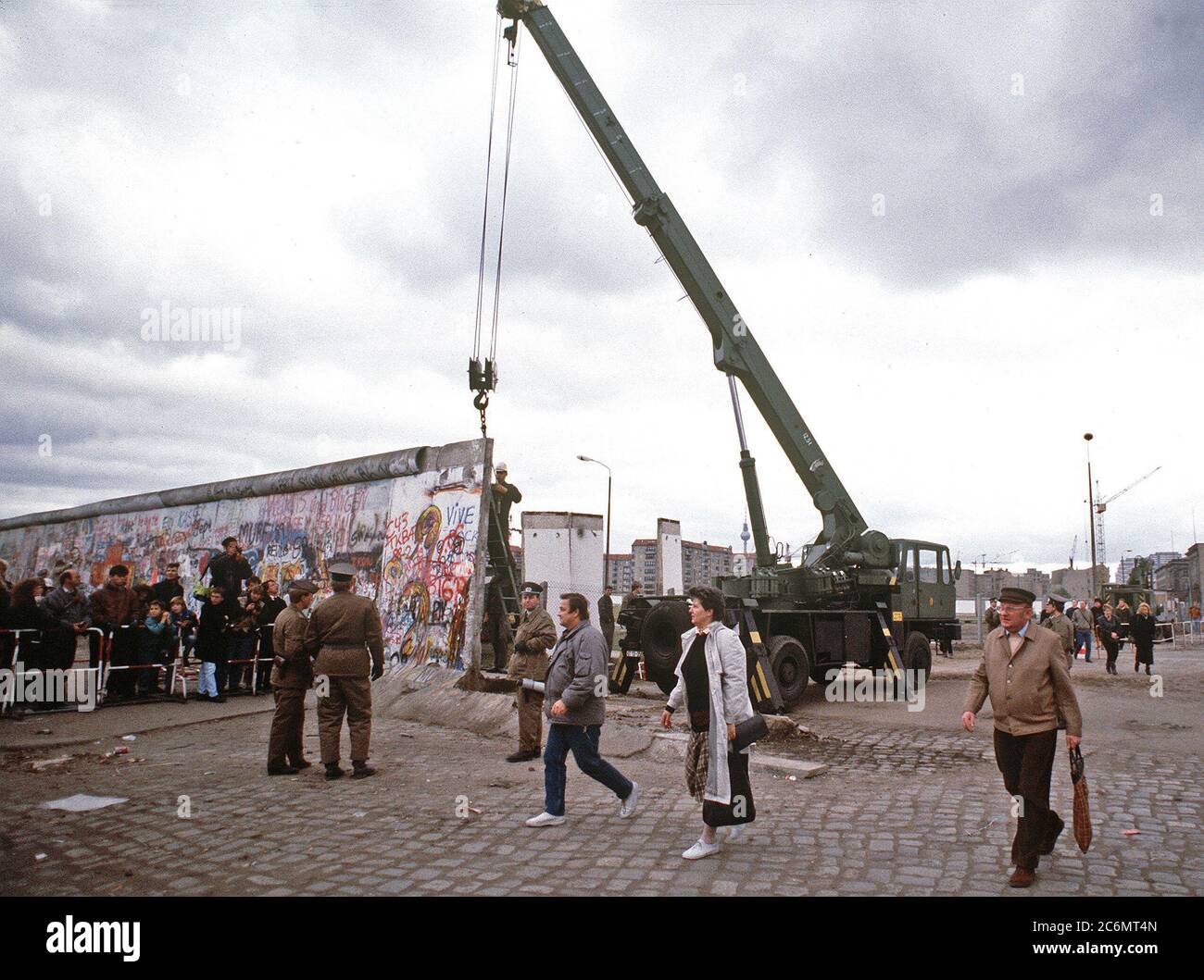 East Berliners cross over to the West as a crane is used to dismantle ...