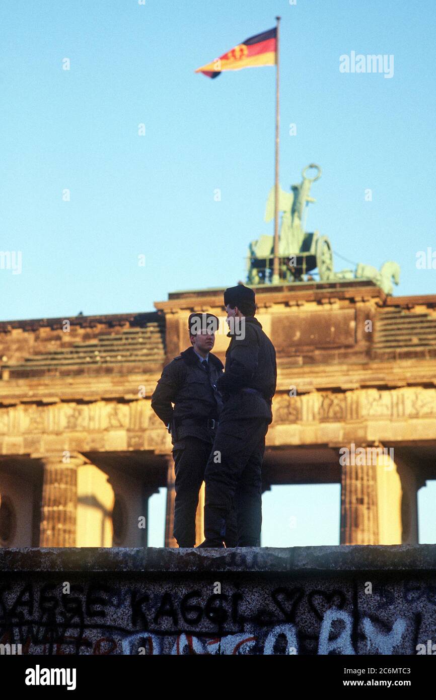 East German guards stand atop the Berlin Wall beside the Brandenburg ...